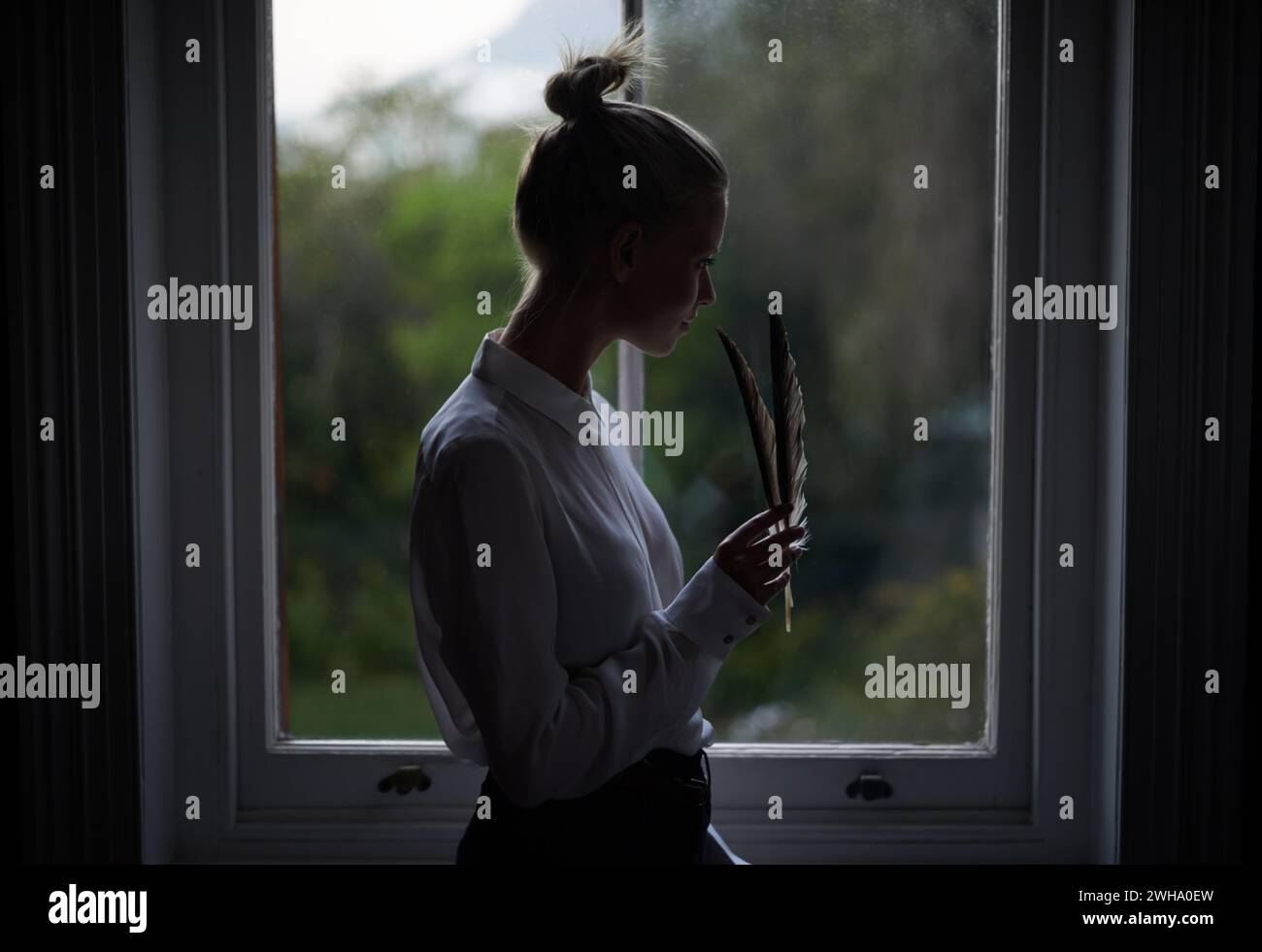 Woman, feather and window in home for writing in dark room and ...