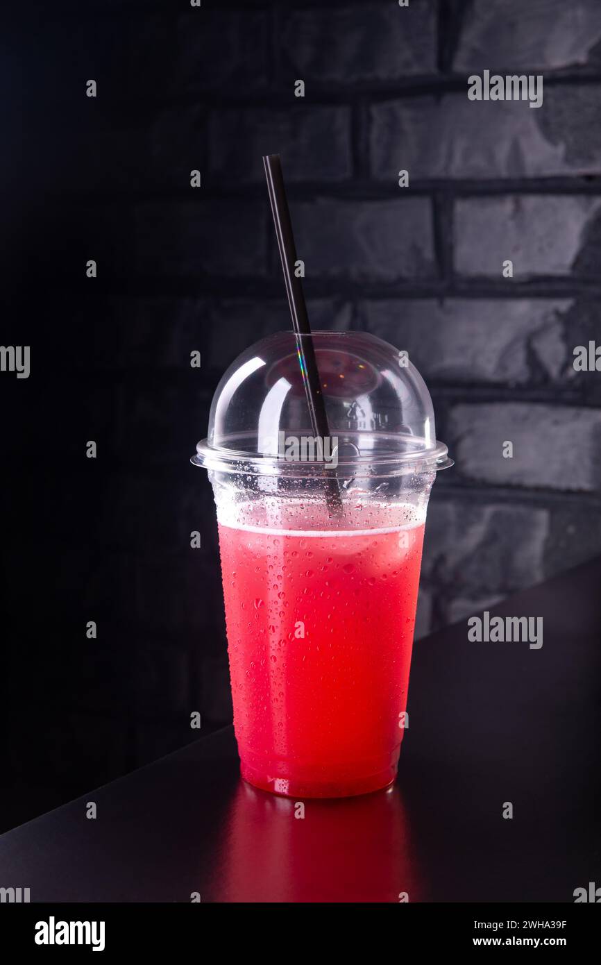 Red lemonade with ice cubes in a plastic glass decorated with an ...