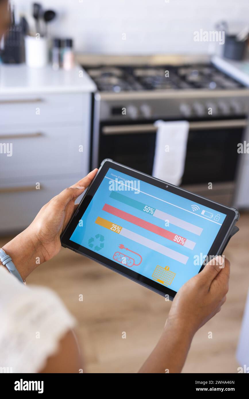 Young biracial woman uses a smart home app on a tablet in a modern ...