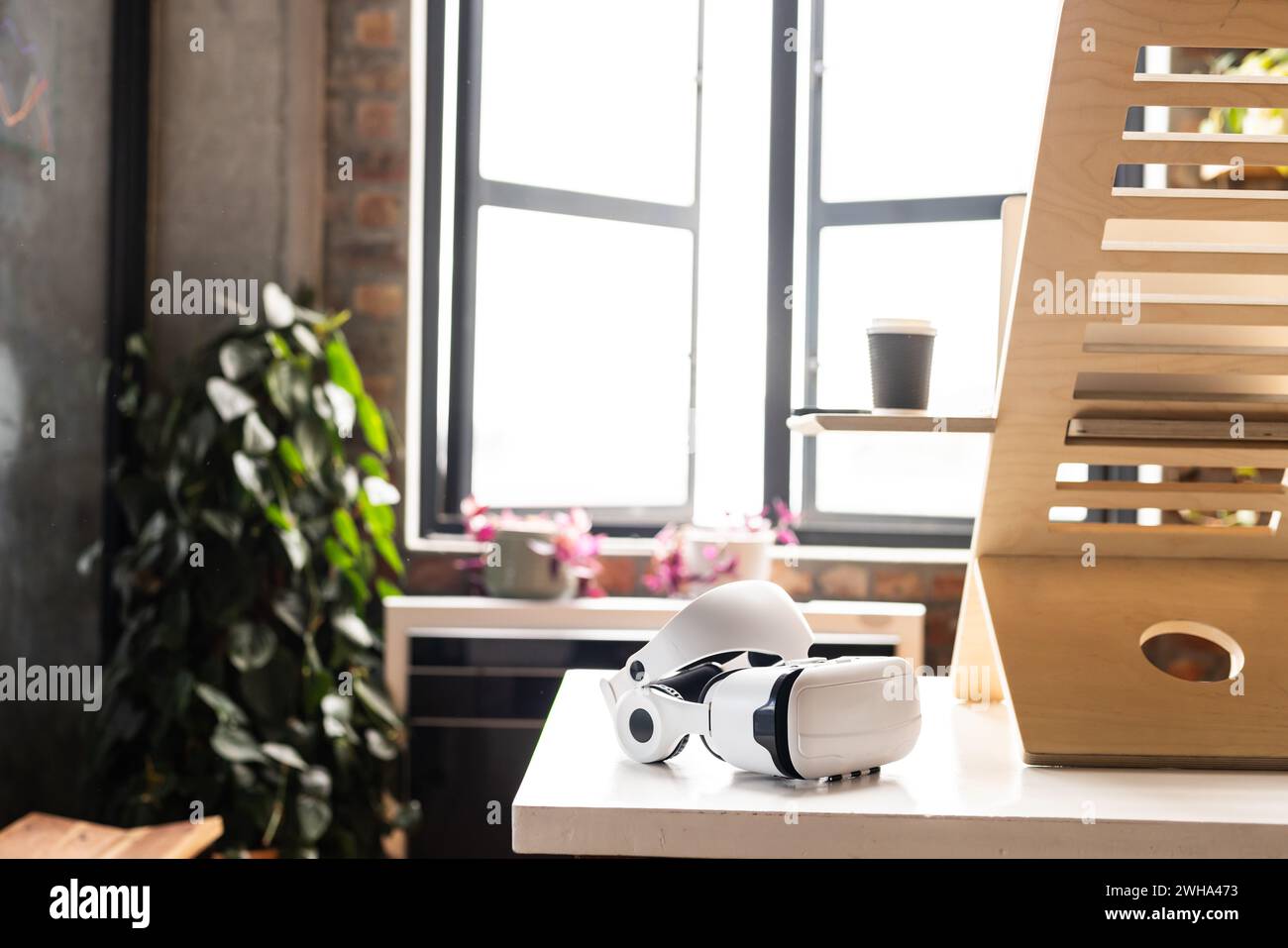 A VR headset rests on a modern desk at home, with copy space. The ...