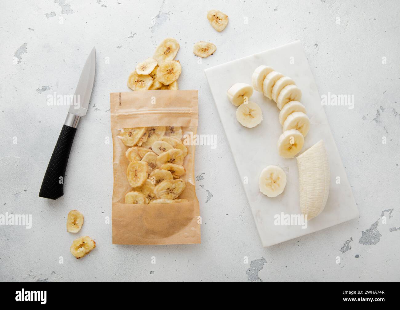 Pack of dried healthy bio banana chips with knife and raw banana.Top ...