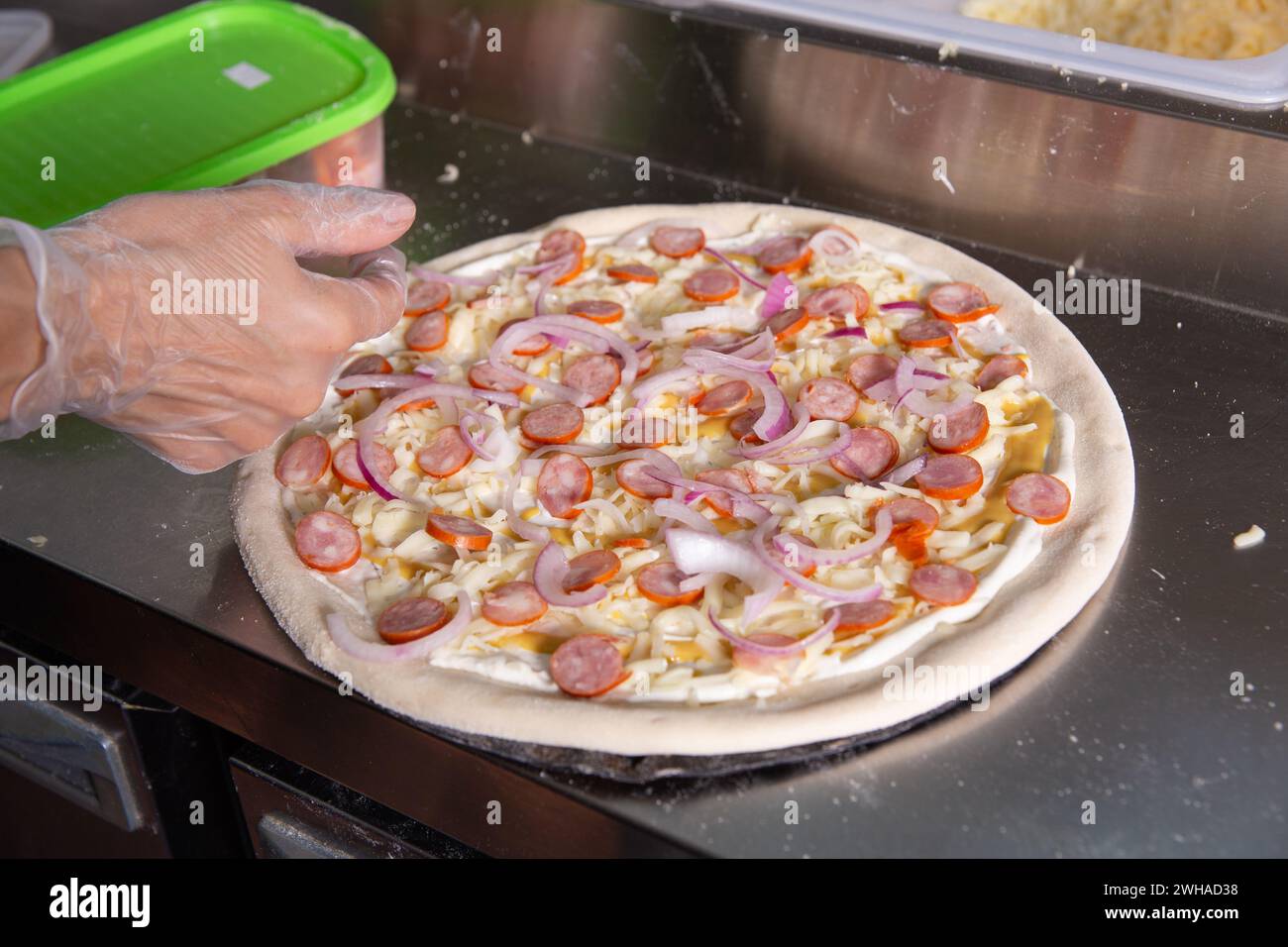 The chef prepares a classic Italian pizza with sausages, mushrooms and ...