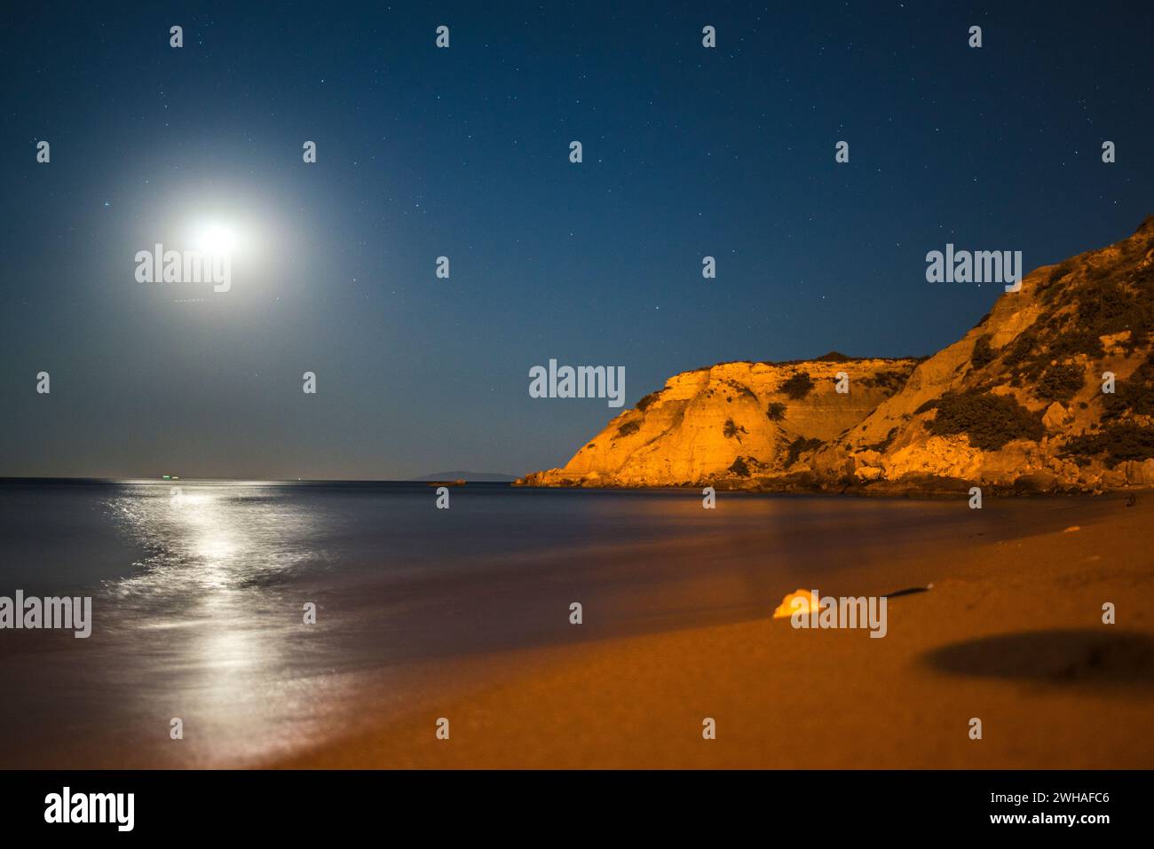 A serene coastal night illuminated by the full moon, casting a tranquil ...