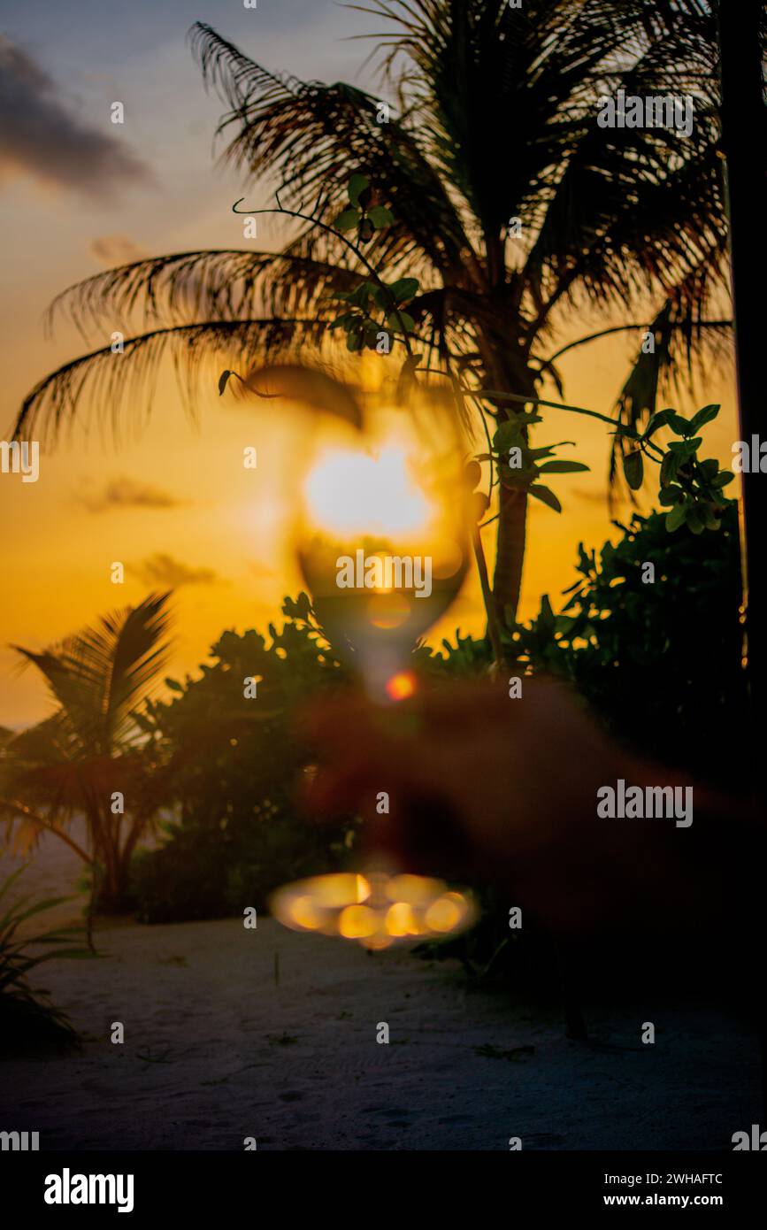 A captivating moment holding a cocktail glass in the Maldivian sunset ...