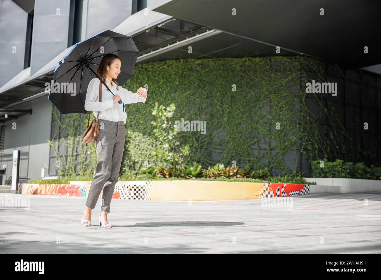 Walking to the office under hot weather, a businesswoman holds an ...
