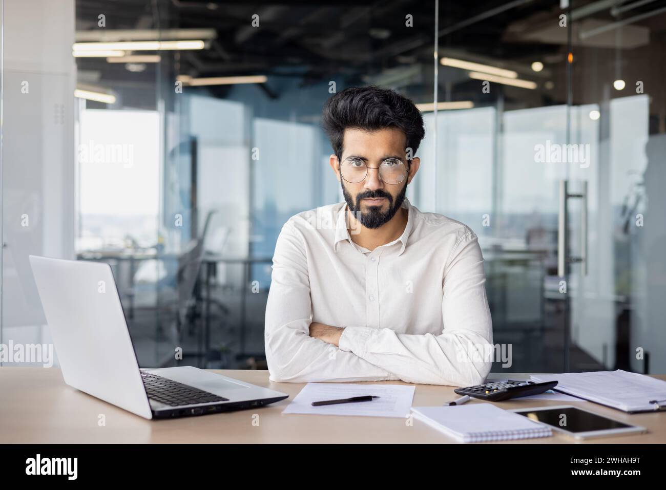 Serious Indian businessman in shirt with beard at office desk ...