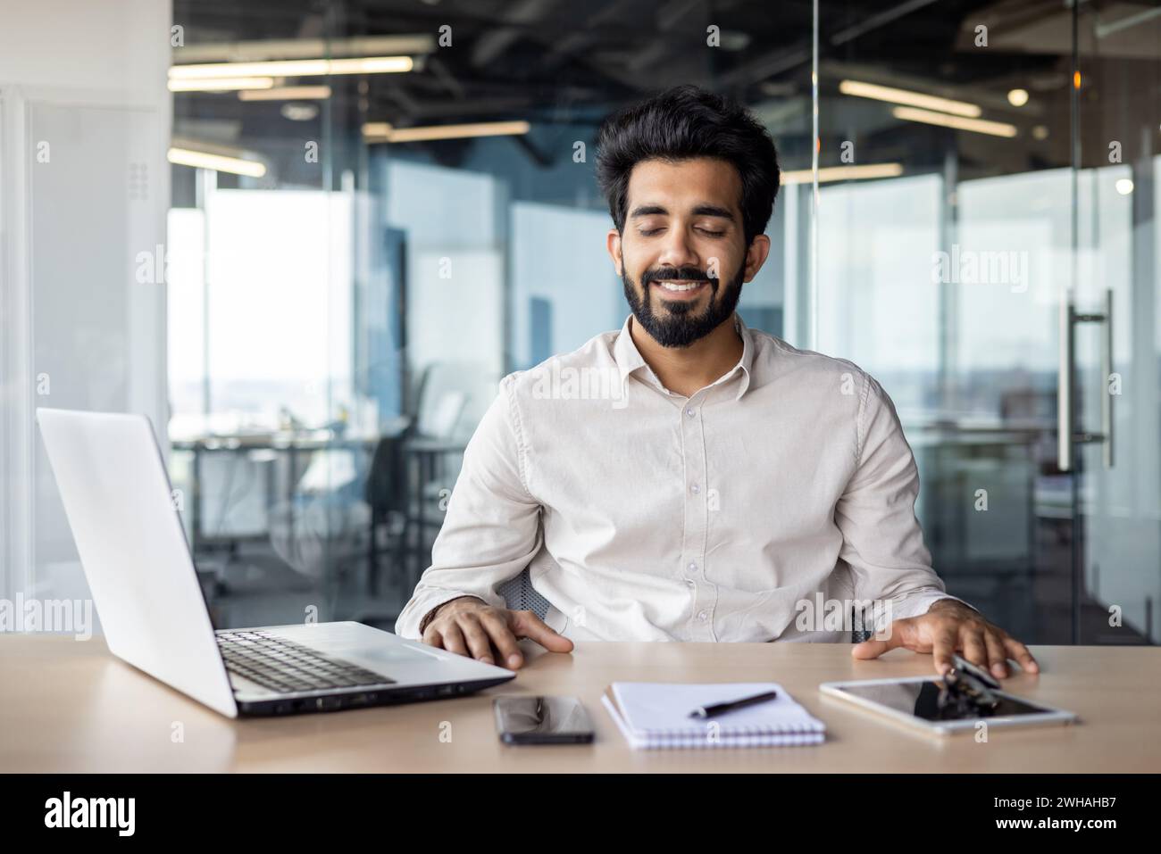 Indian businessman in a modern office working on a laptop with a ...