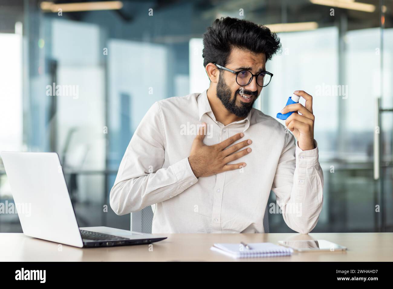 Indian businessman at work feeling sick, using inhaler while suffering ...