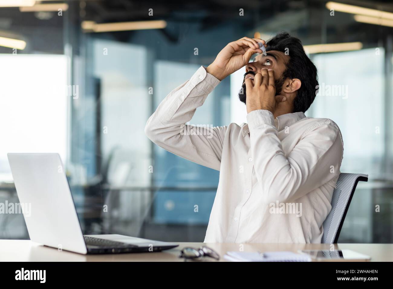 Indian office worker at his desk showing signs of exhaustion and ...