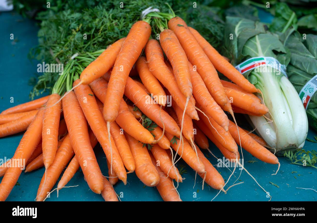 Fresh summer carrots on outdoor market with seasonal local vegetables ...