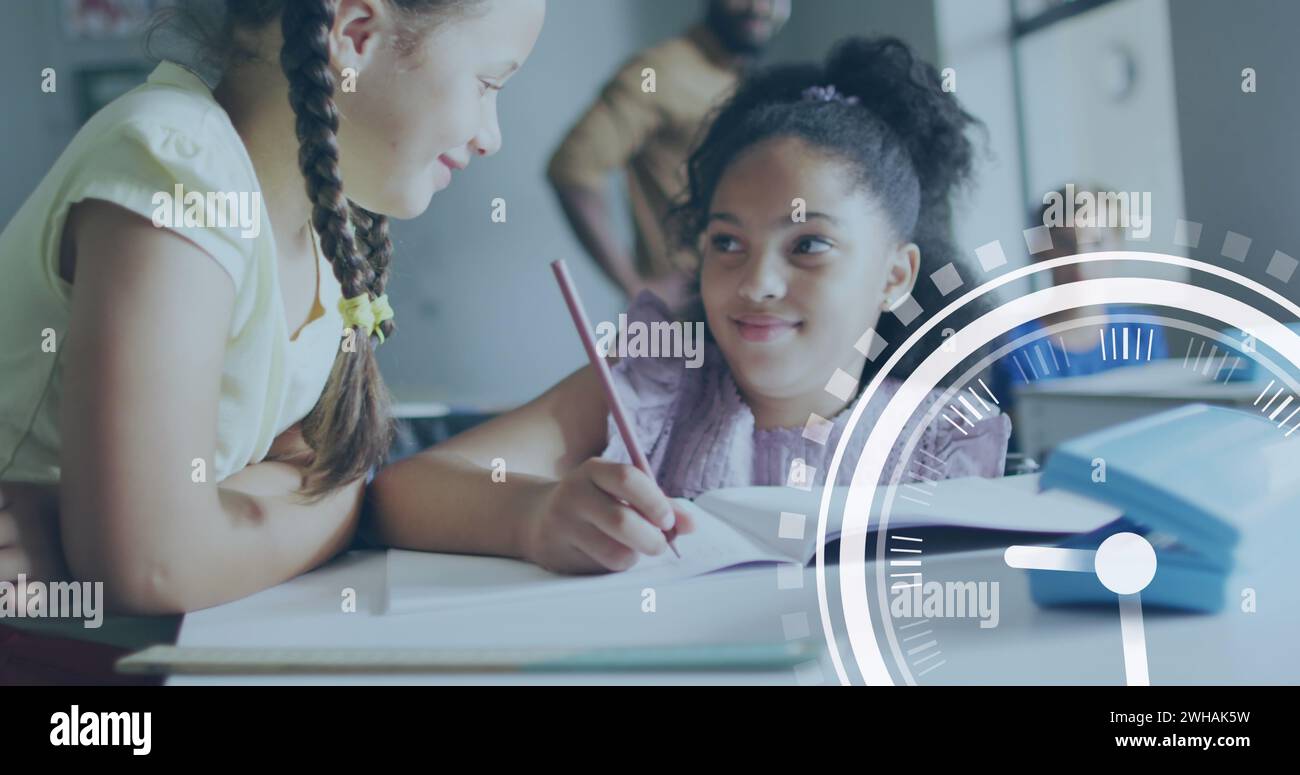 Image of clock over diverse schoolgirls talking at desk in class Stock ...