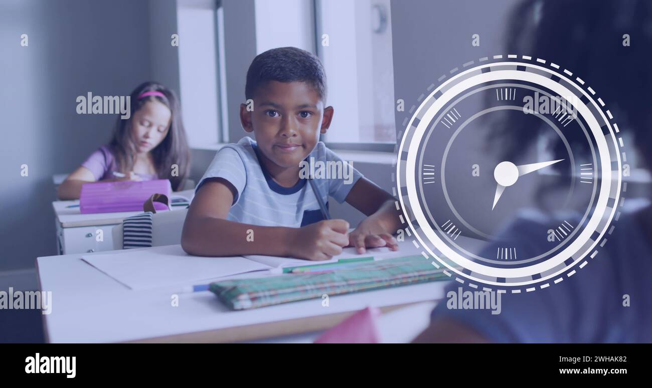 Image of clock over smiling biracial boy sitting at desk in diverse ...
