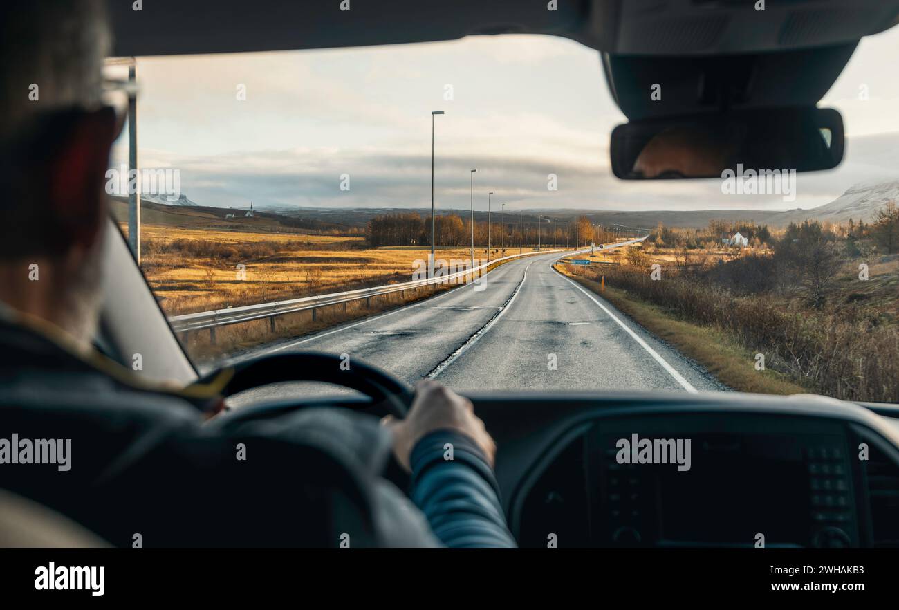 Back view of anonymous person driving vehicle along lonely asphalt ...