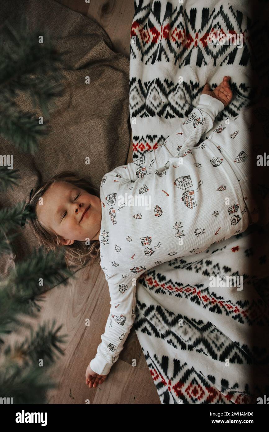 Little girl lays under tree, Christmas serenity Stock Photo - Alamy