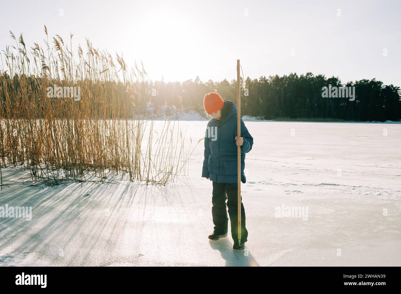 boy using an ice stick to test breaking the ice on a frozen lake Stock ...