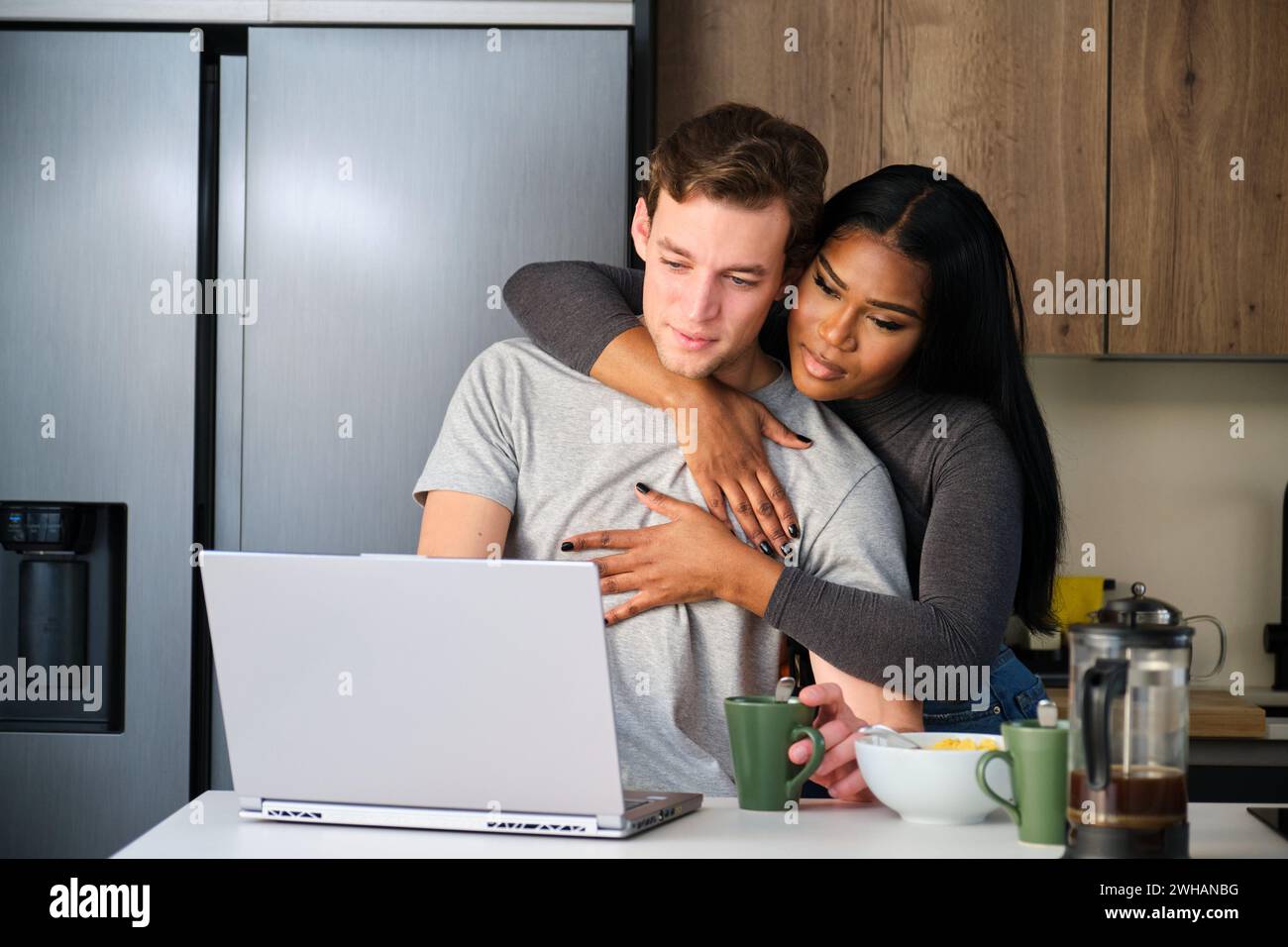 Multiethnic couple, man working while his wife hugging him Stock Photo ...