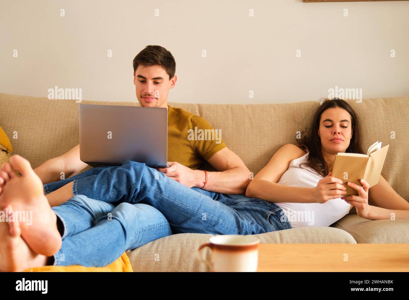 Man watching a movie while his girlfriend reading a book Stock Photo ...
