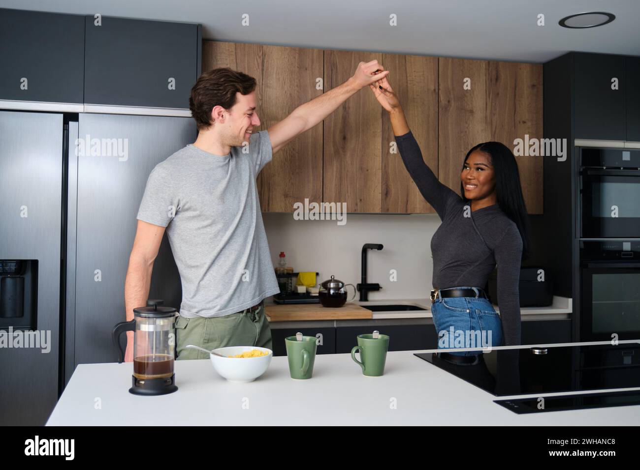 Multiethnic happy couple dancing at kitchen Stock Photo - Alamy