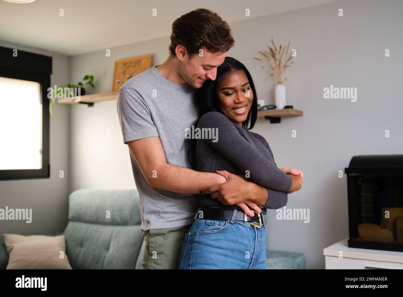 Multiethnic couple hugging and dancing happily at home Stock Photo - Alamy