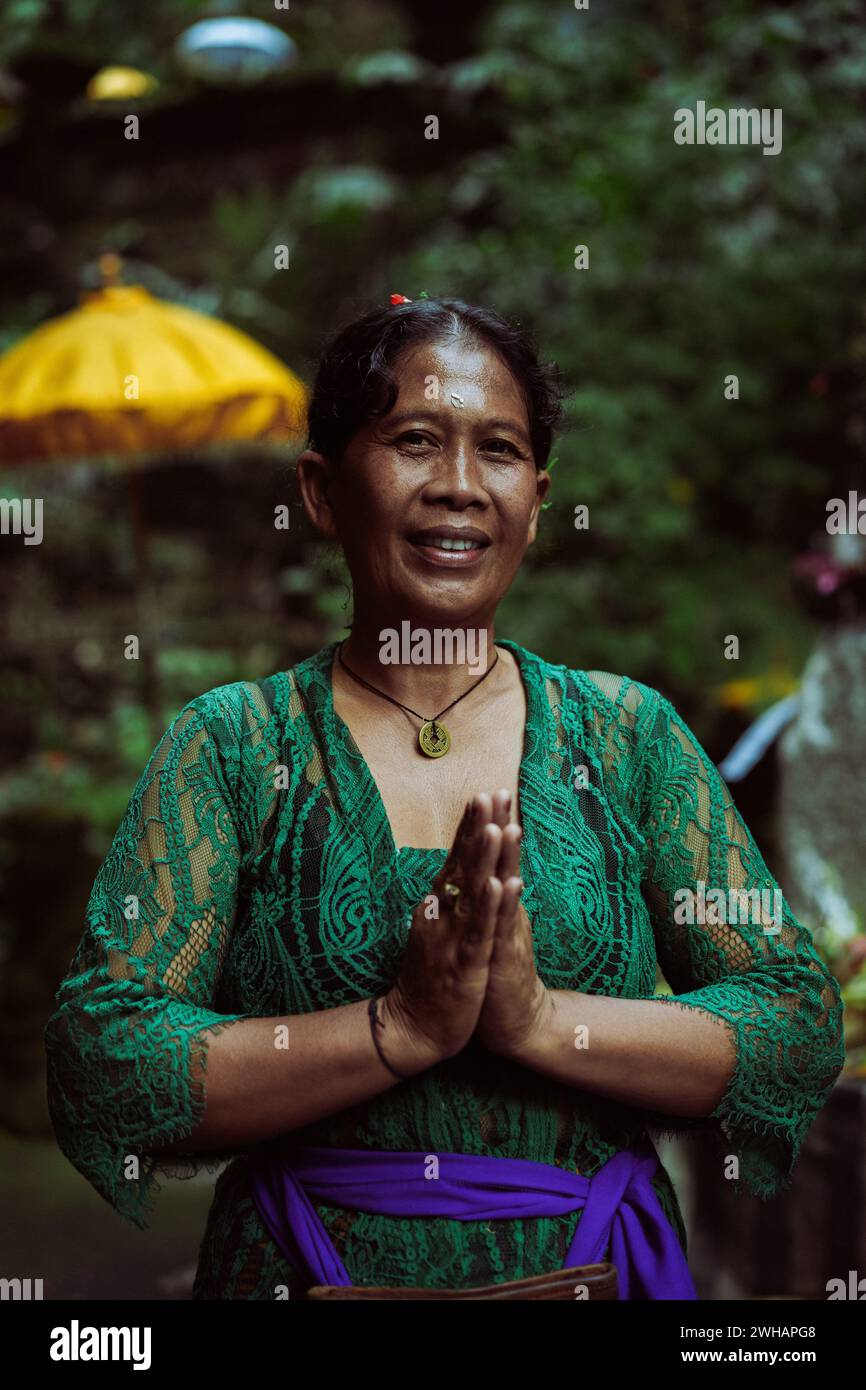 Balinese woman in traditional dress prays in ceremony at temple, Bali ...