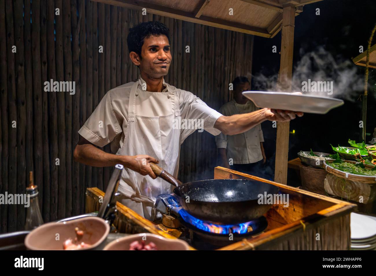 Waiter with a maldivian dish in the water restaurant of Six Senses ...