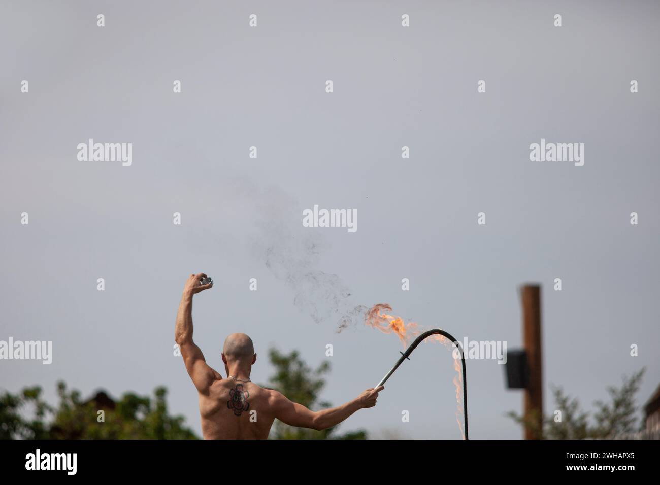 Behind view of muscly bald man with flaming whip Stock Photo - Alamy