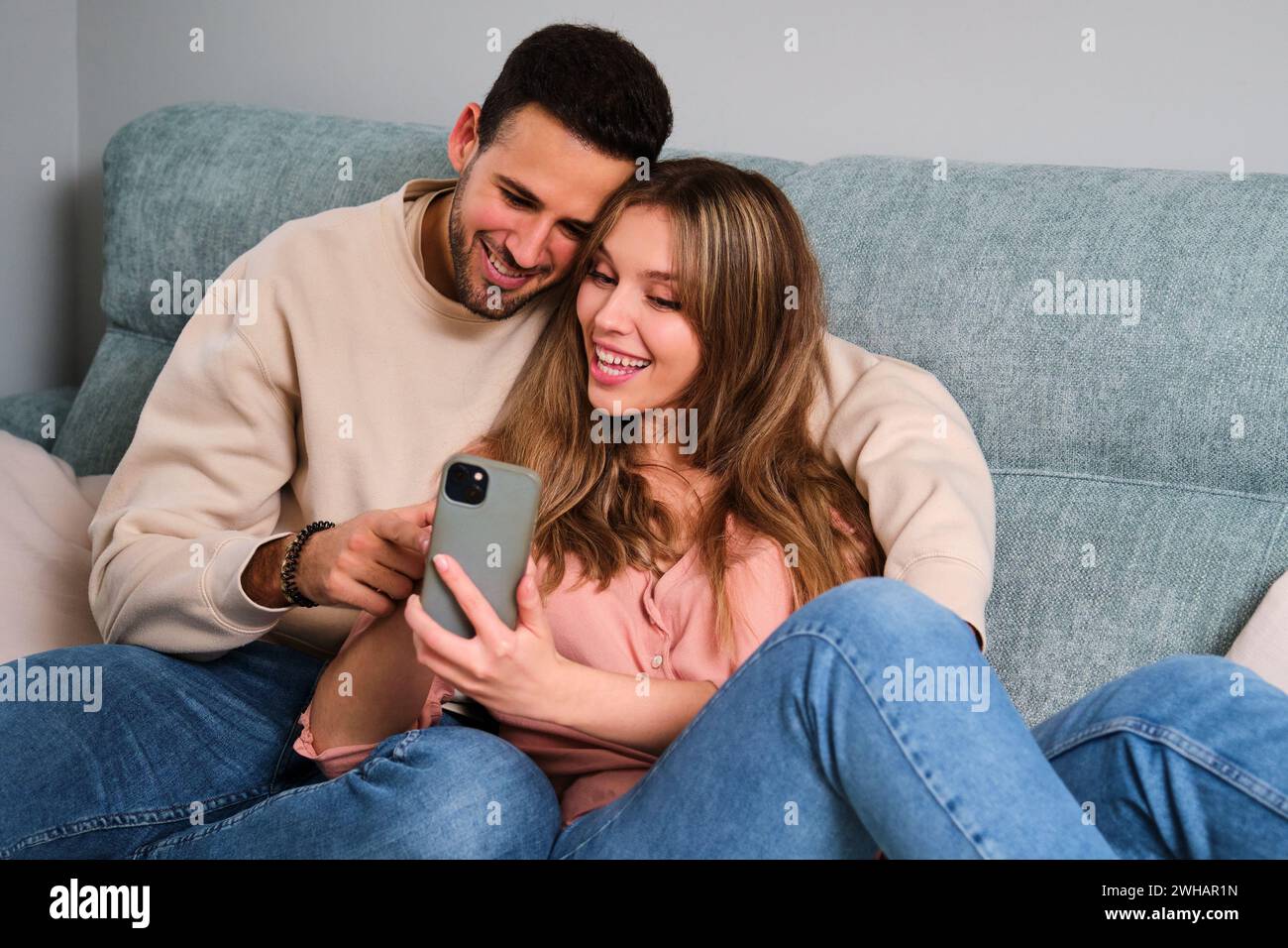 Spanish couple laughing while checking the smartphone Stock Photo - Alamy