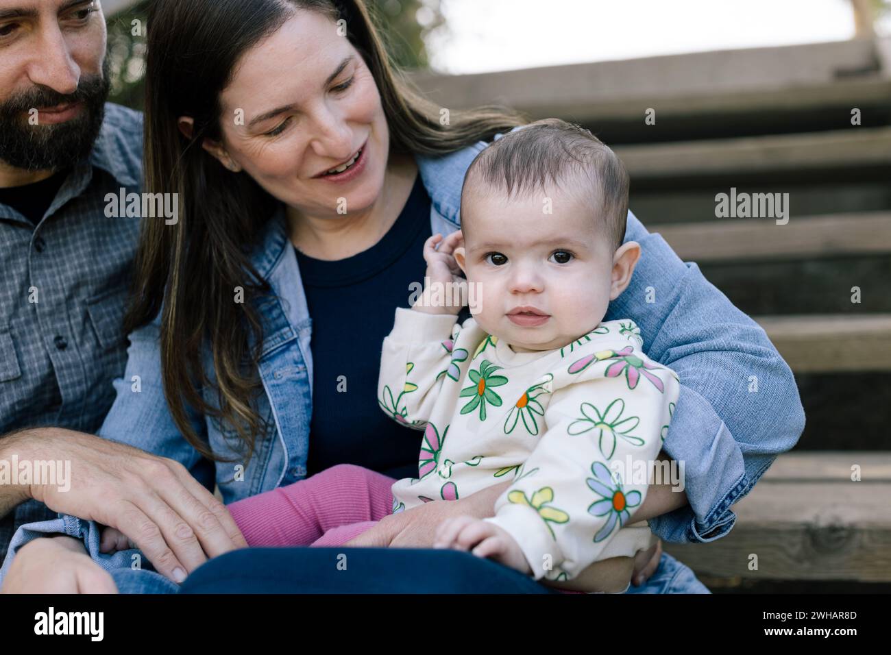 Adoring parents look at baby girl as they sit outside Stock Photo - Alamy