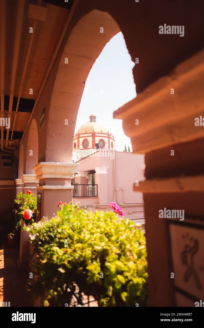 Spanish building archway with plants and church in the view Stock Photo ...