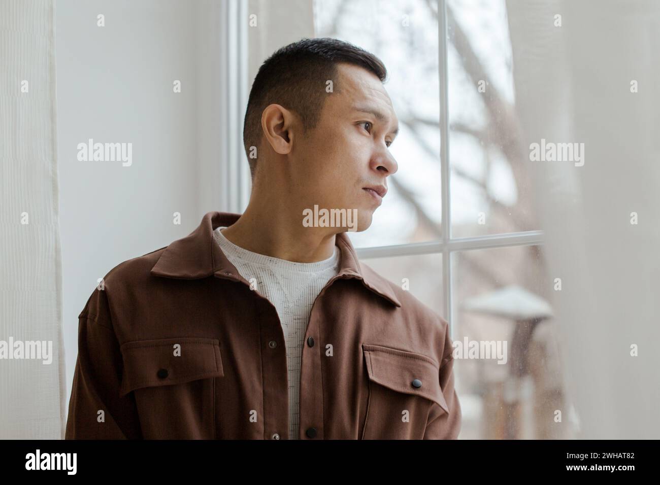 Portrait of sad pensive Asian man near window Stock Photo - Alamy
