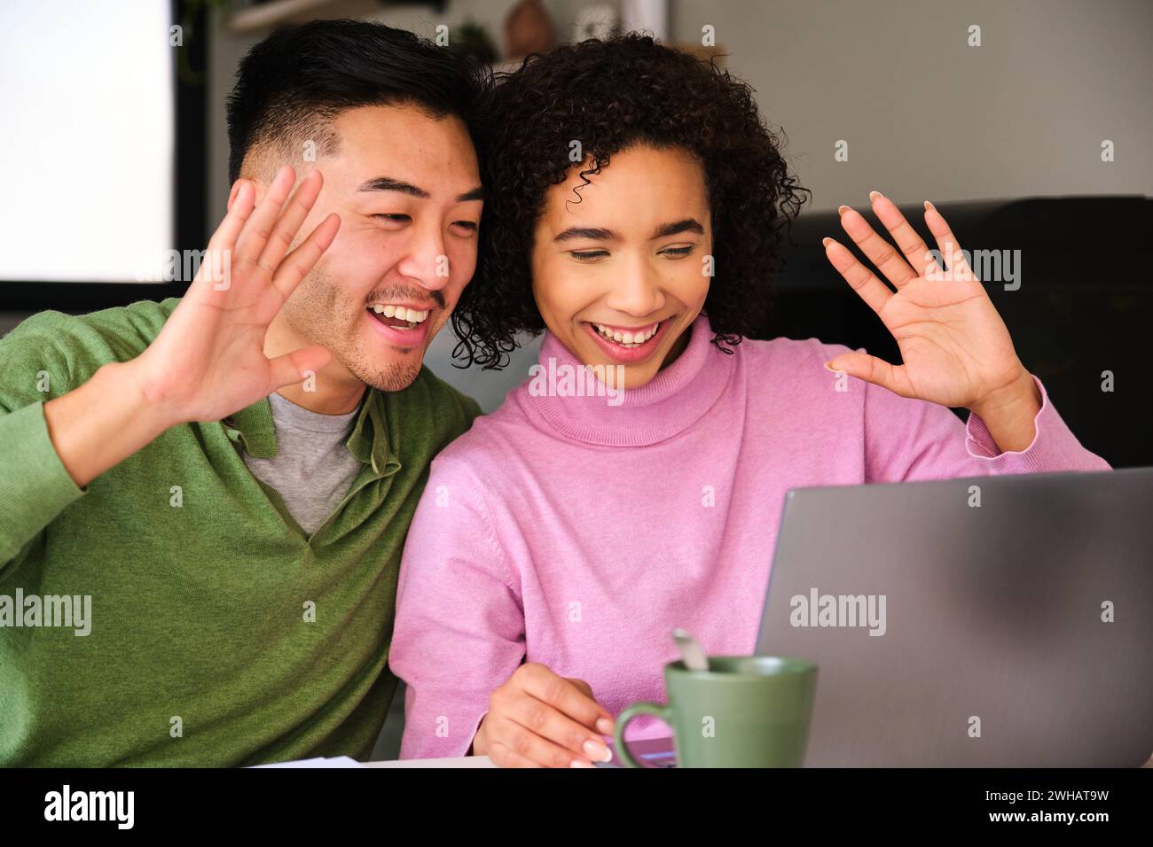 Multiethnic happy couple wave on a video call with family or friends ...