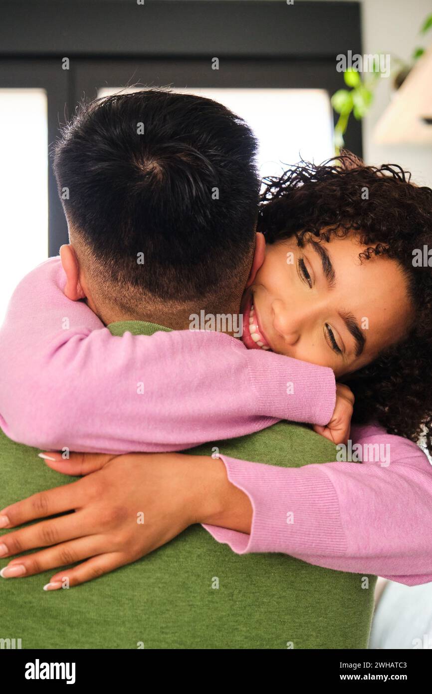 Latin woman hugging her Asian boyfriend at home Stock Photo - Alamy
