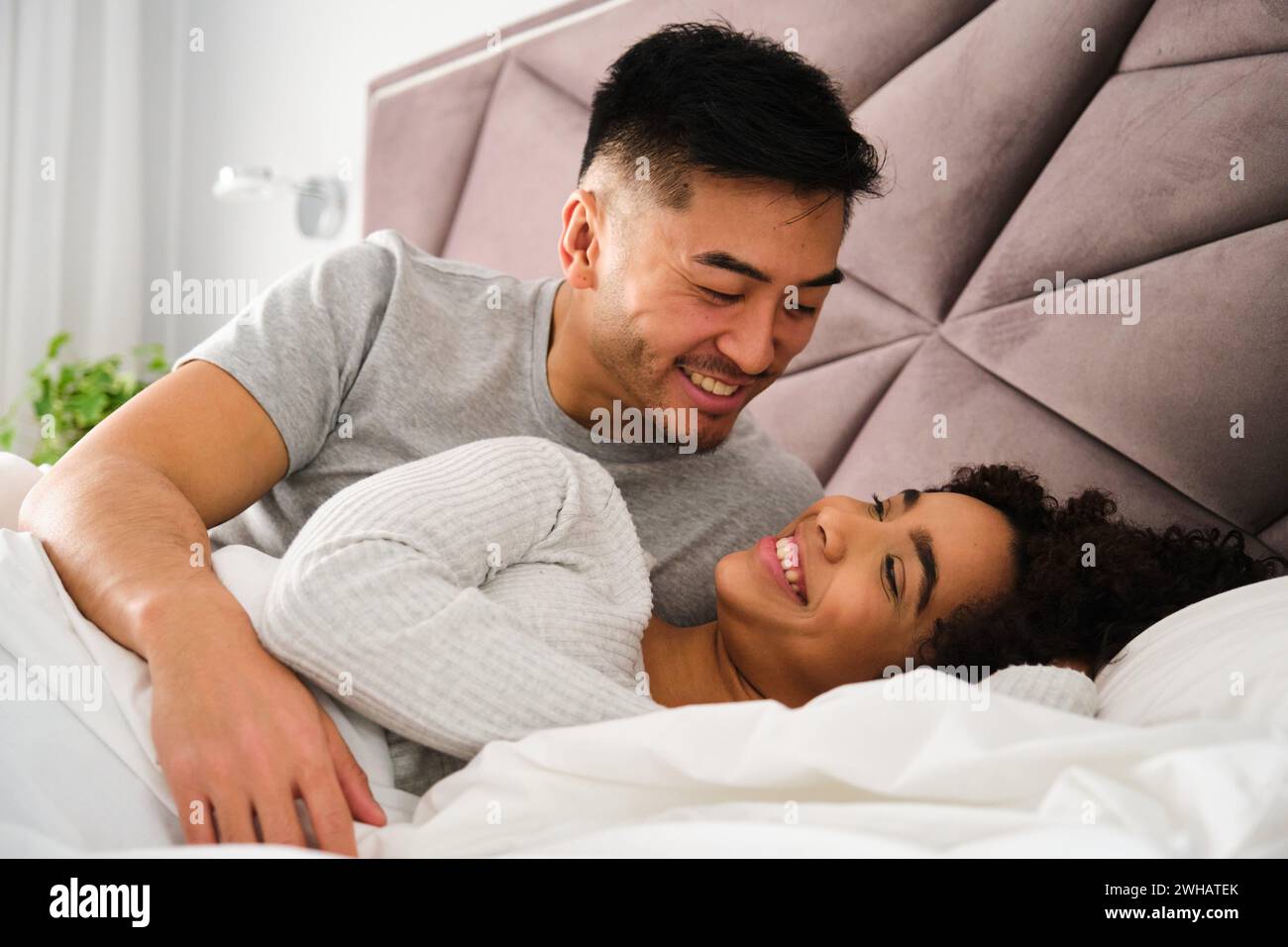 Diverse romantic couple wake up together in bed during honeymoon Stock ...