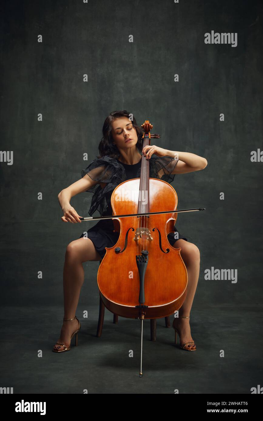 Elegant, passionate musician, beautiful woman in black dress sitting ...