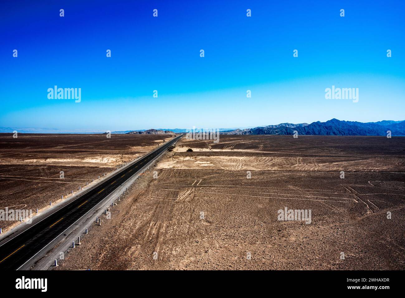 Asphalt road cuts through the desert like a straight line of black tar ...