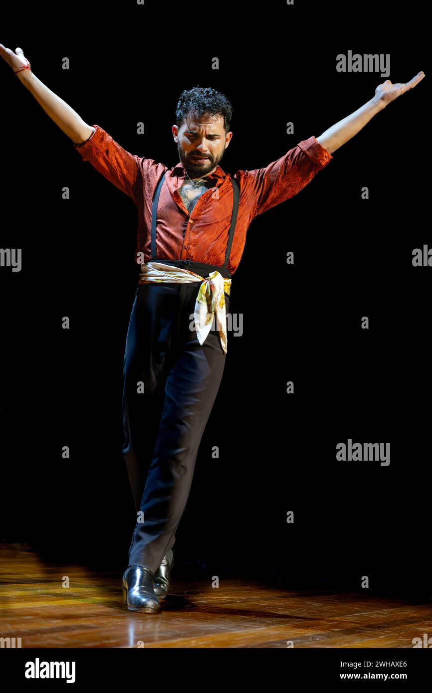 A male flamenco dancer opens his arms wide, channeling the intensity of ...