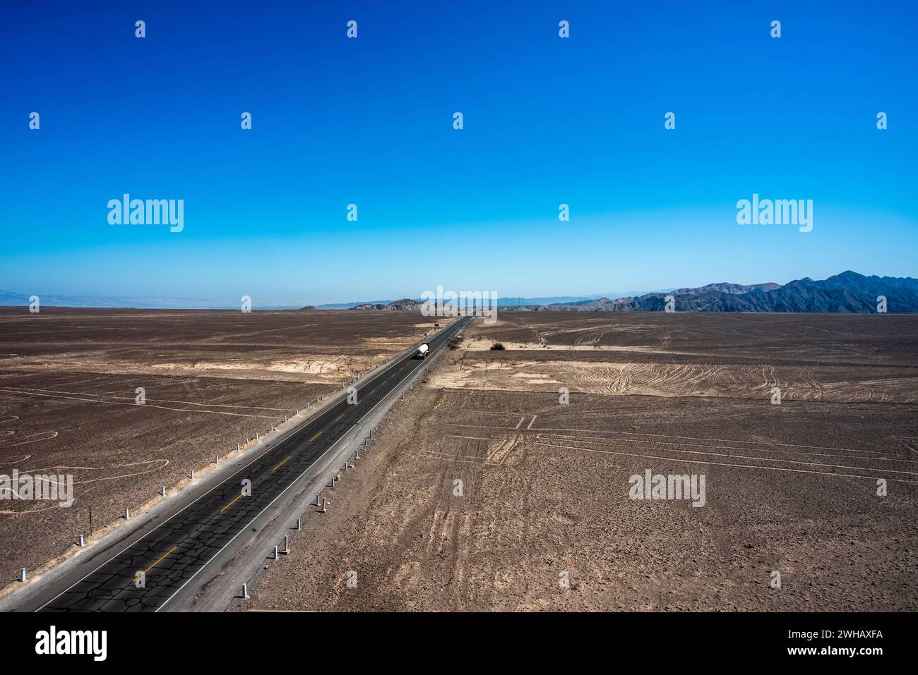 Asphalt road cuts through the desert like a straight line of black tar ...