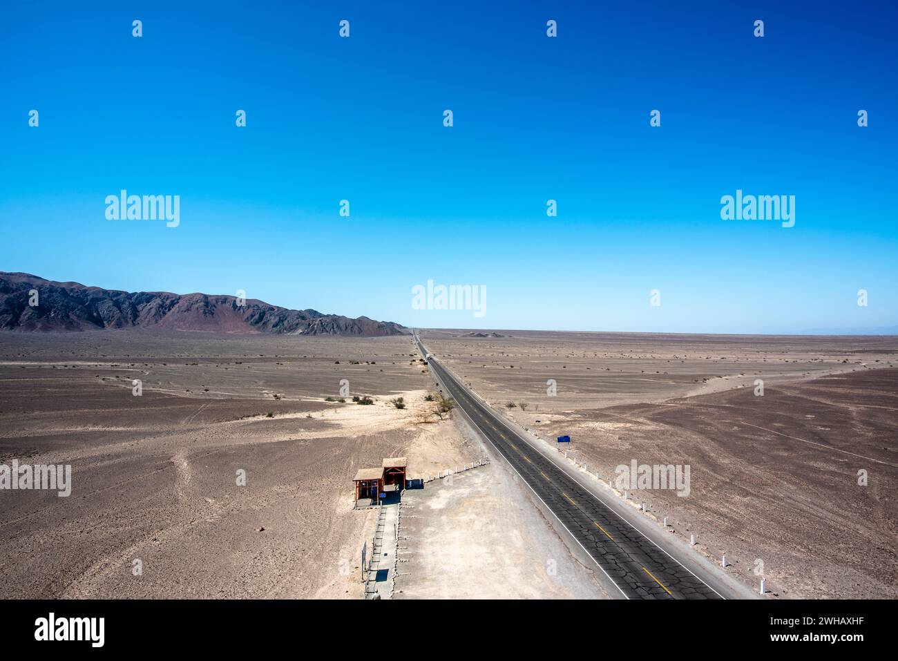 Asphalt road cuts through the desert like a straight line of black tar ...