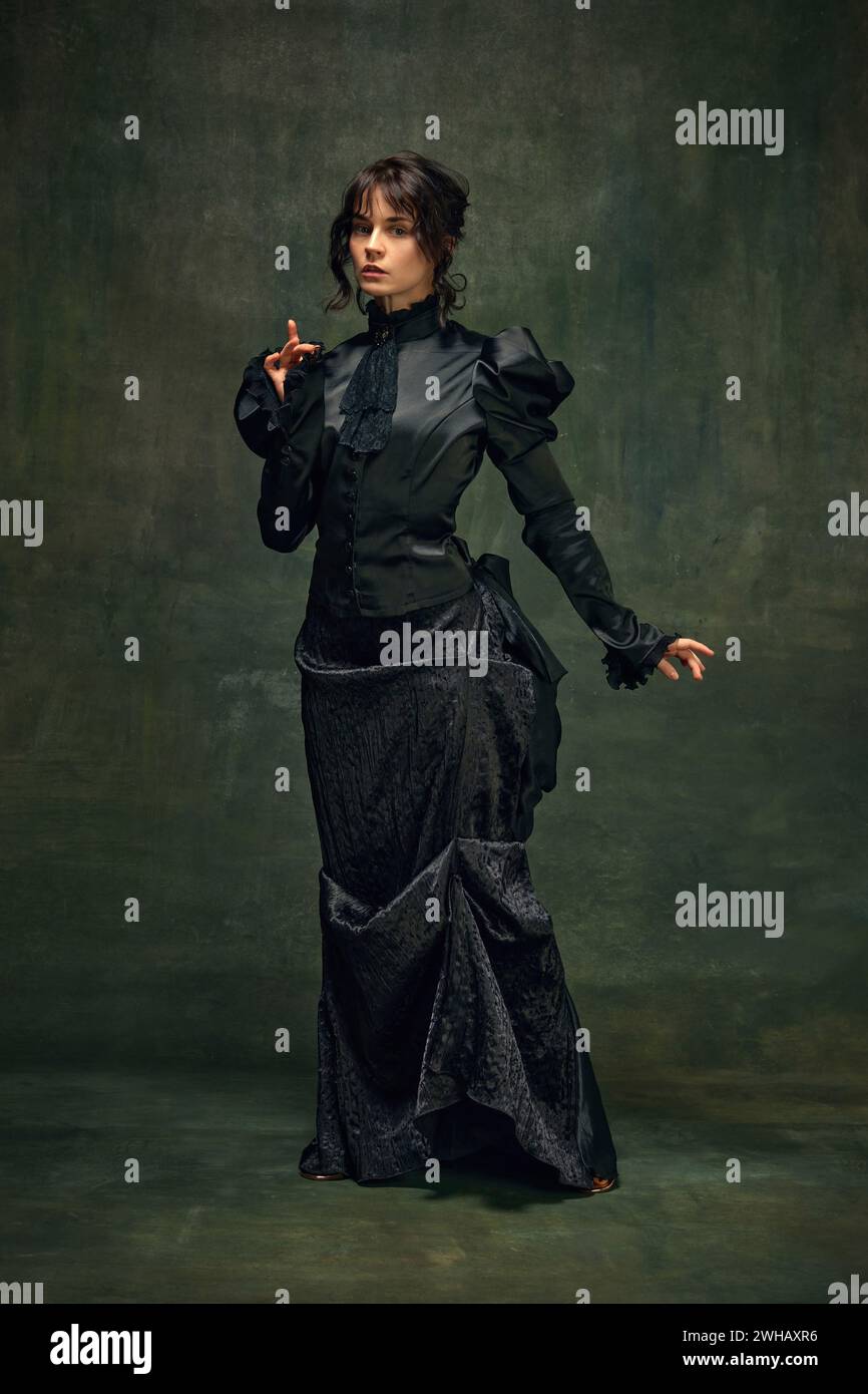 Elegant, beautiful woman in Victorian style black dress, standing with ...