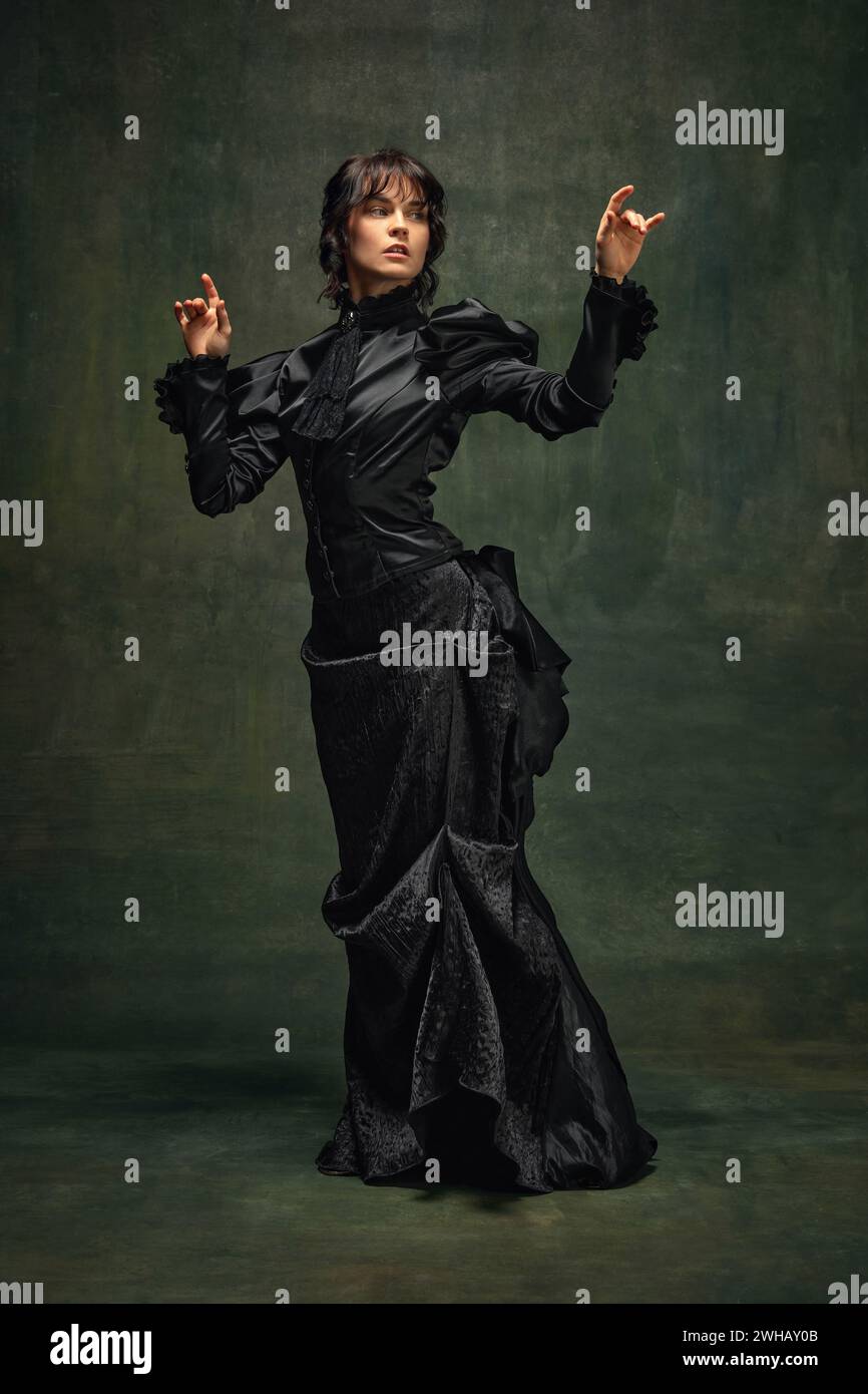 Woman in Victorian style black dress, standing in a dramatic pose ...