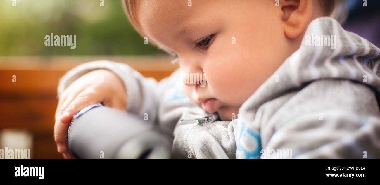 Cute baby boy is deeply engrossed in examining an object with curiosity ...