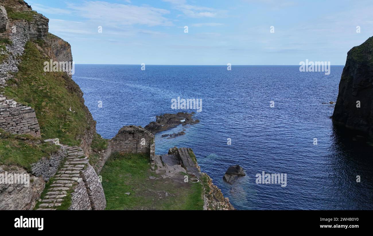 A scenic landscape featuring a slender cliff edge amidst lush grass and ...