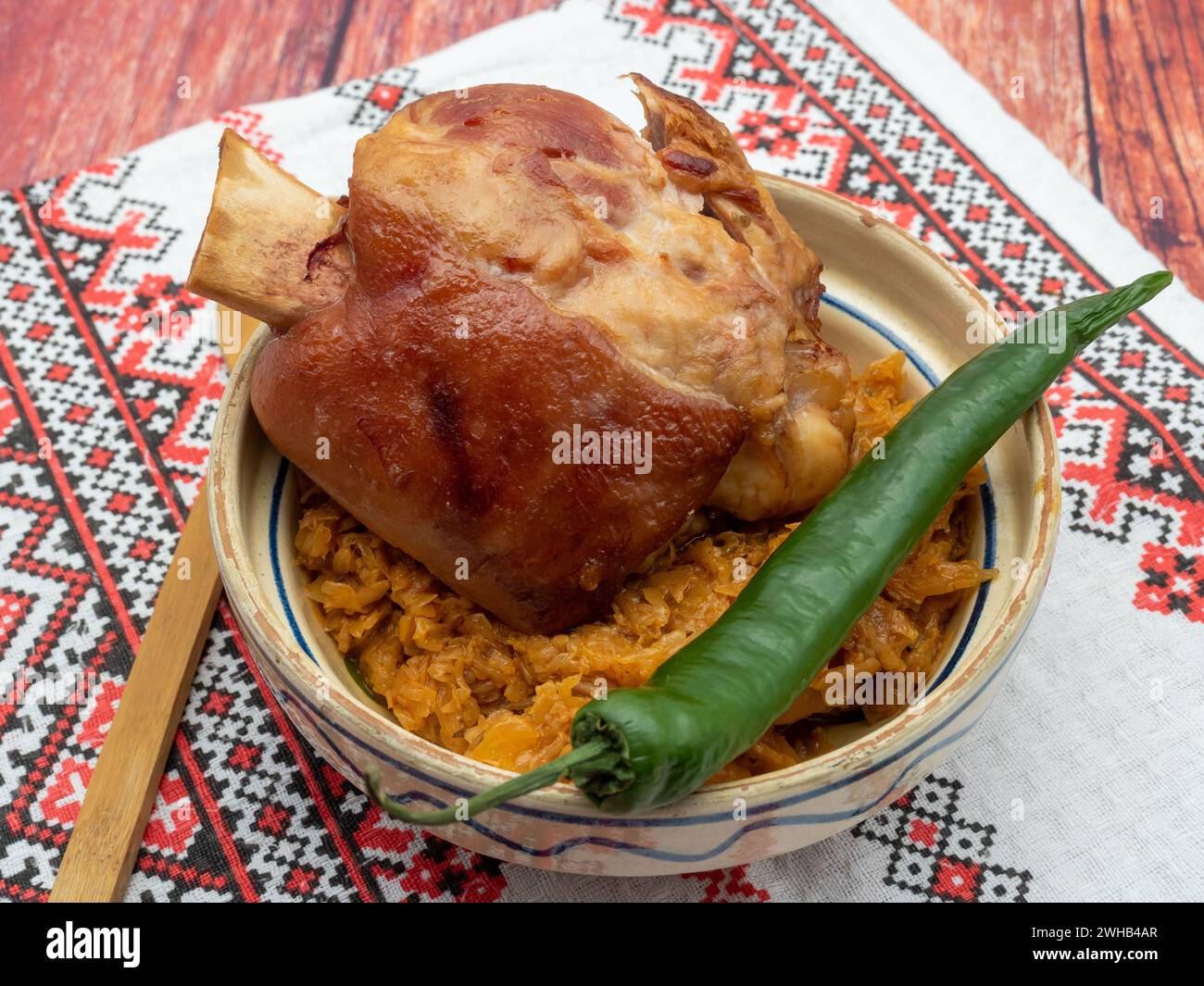 A close-up of a succulent pork knuckle served with cabbage and spicy ...