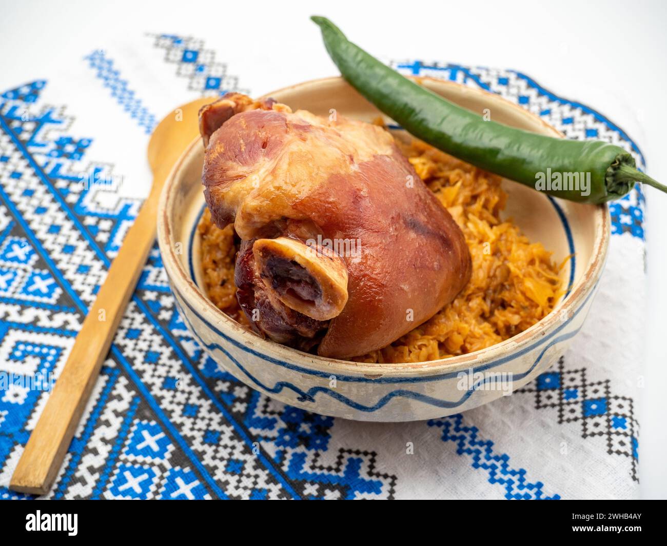 A close-up of a succulent pork knuckle served with cabbage and spicy ...