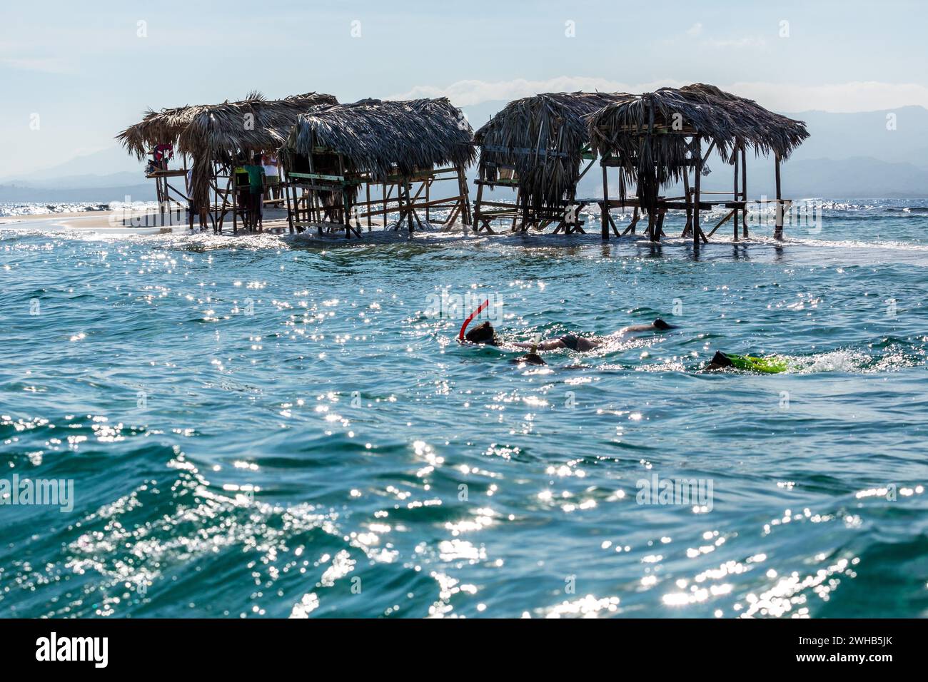 Tourists snorket as waves break over tiny Paradise Island, a small ...