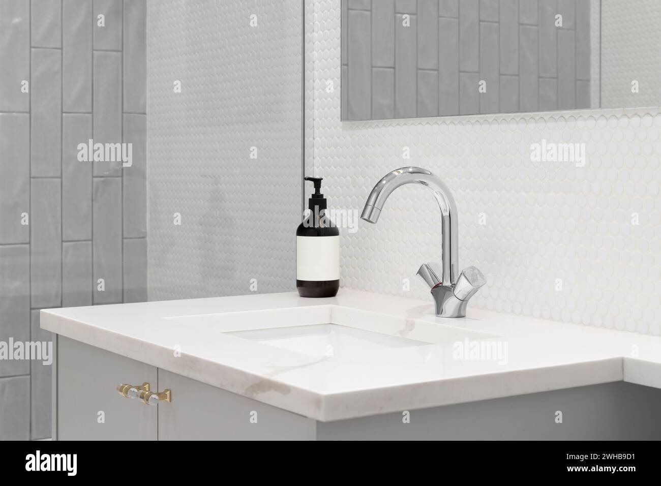 A bathroom faucet detail with a chrome faucet, white marble countertop ...