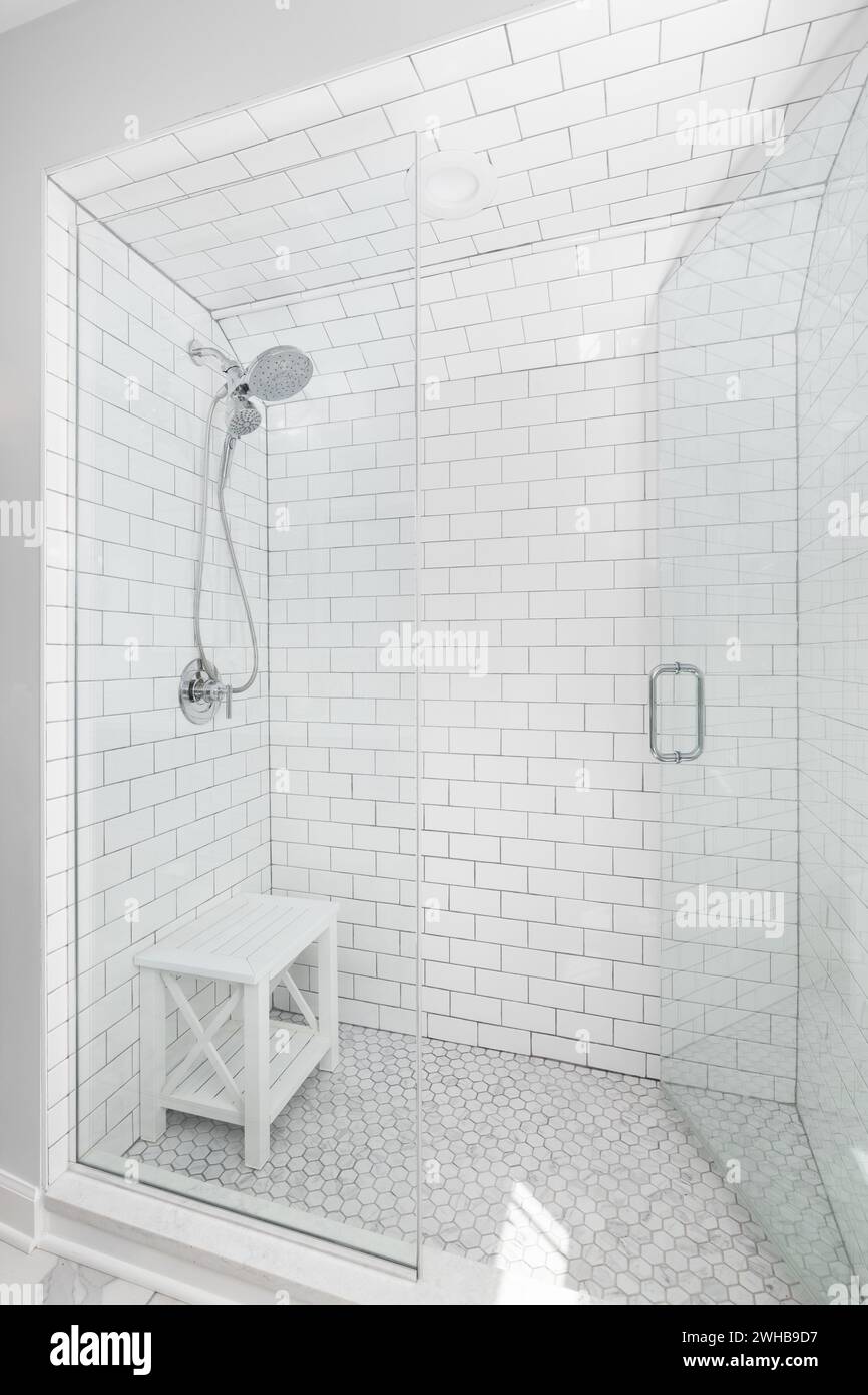 A walk-in shower with subway tile walls, marble hexagon tile floor, and ...