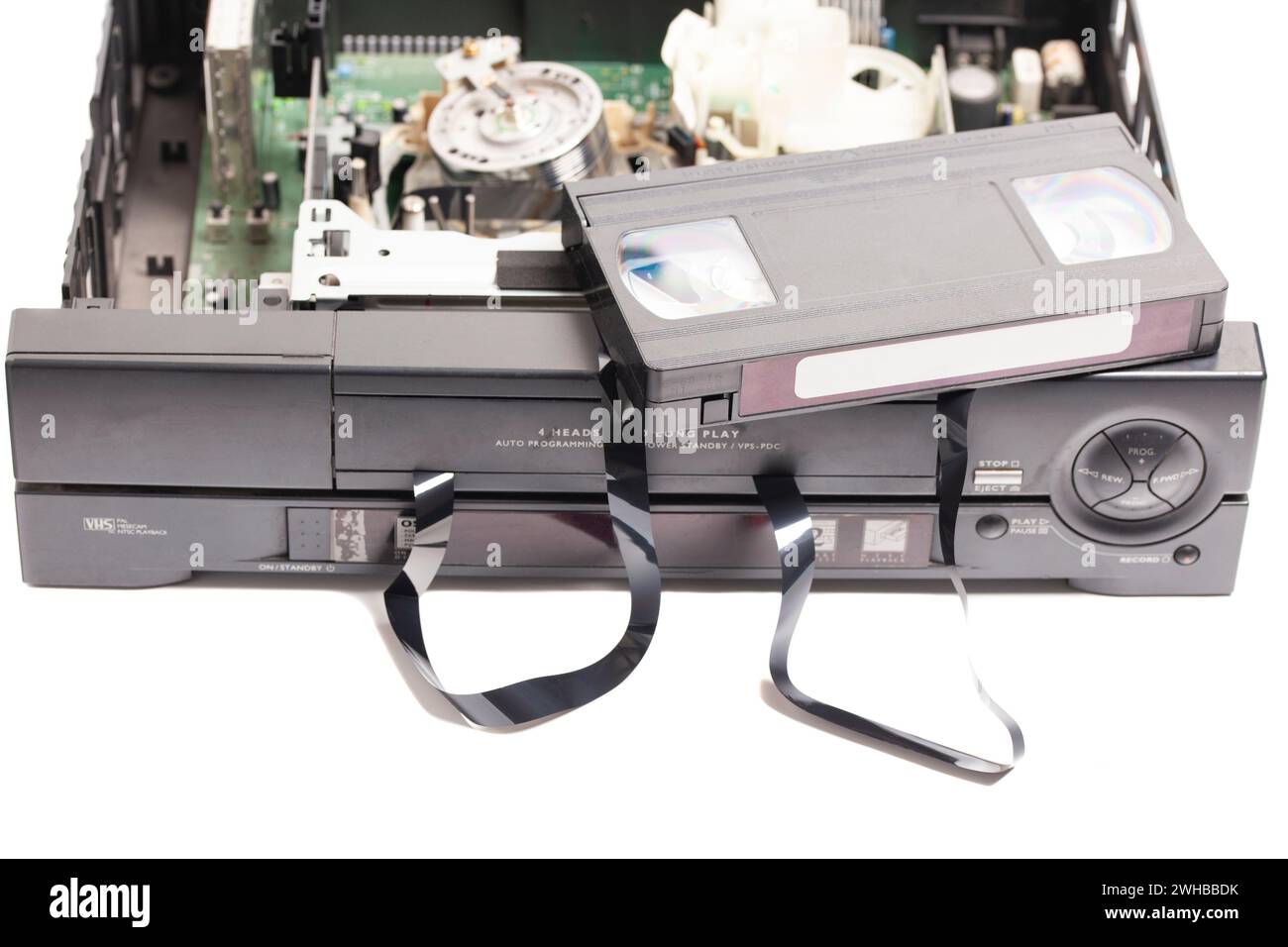 Retro disassembled video cassette recorder with broken VHS cassette with unwound tape isolated ...