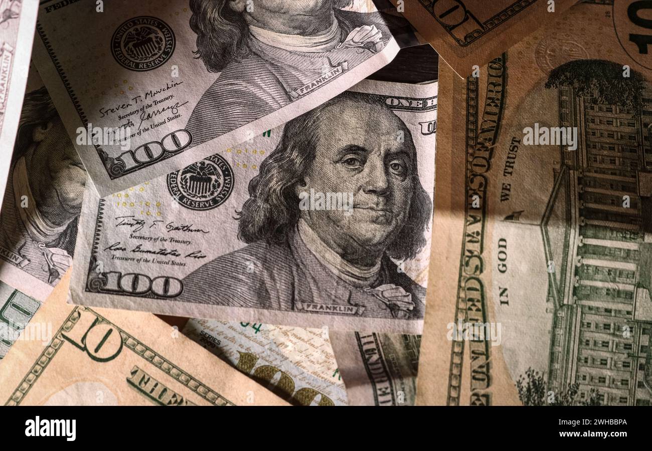 American 100 and 10 dollar bills on a dark table Stock Photo - Alamy