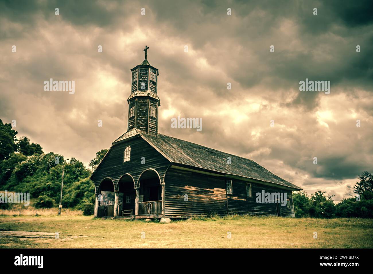 An old black wooden church on Chiloe with a single church tower and ...